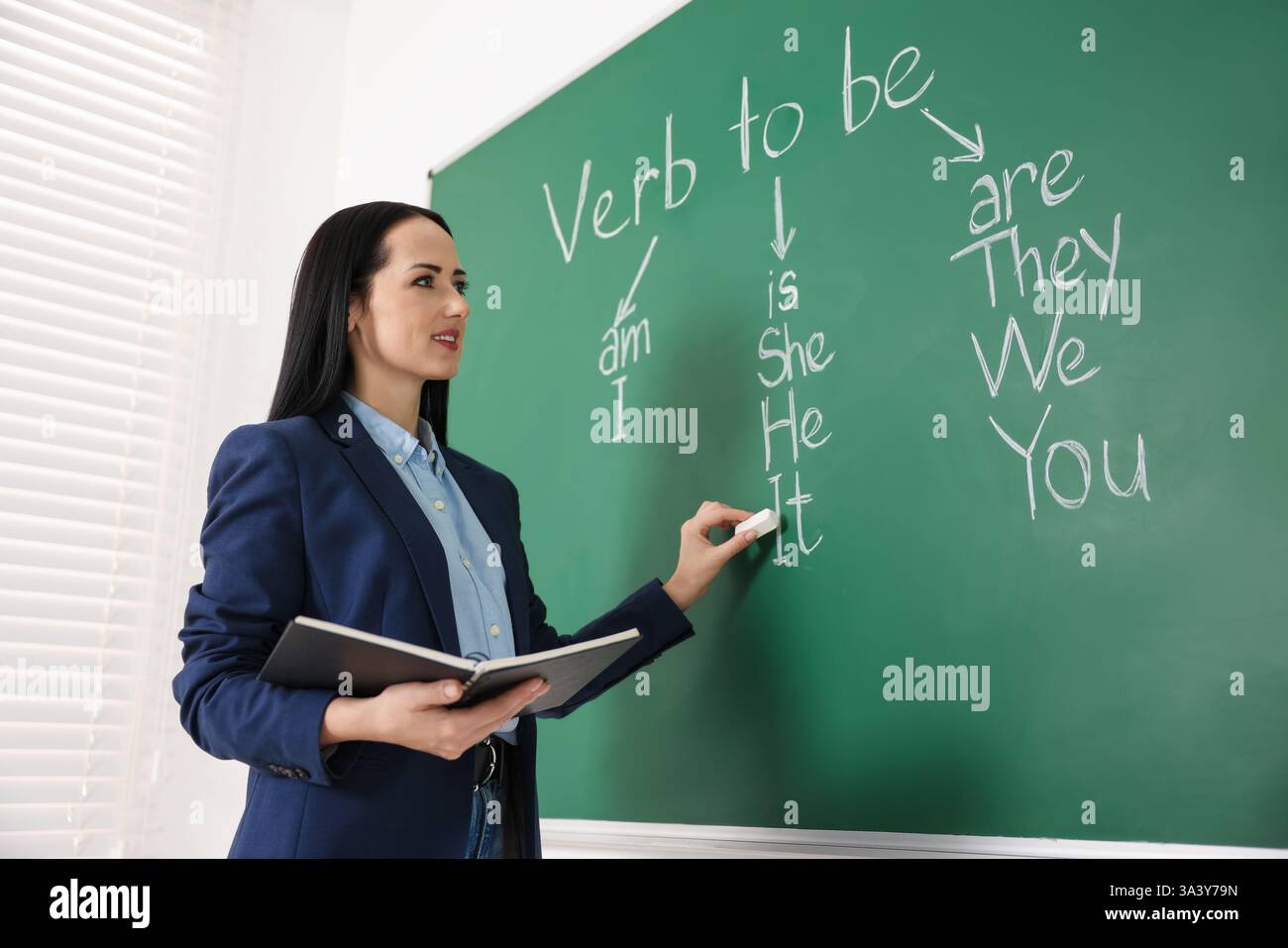 English teacher during lesson near chalkboard in classroom Stock Photo ...