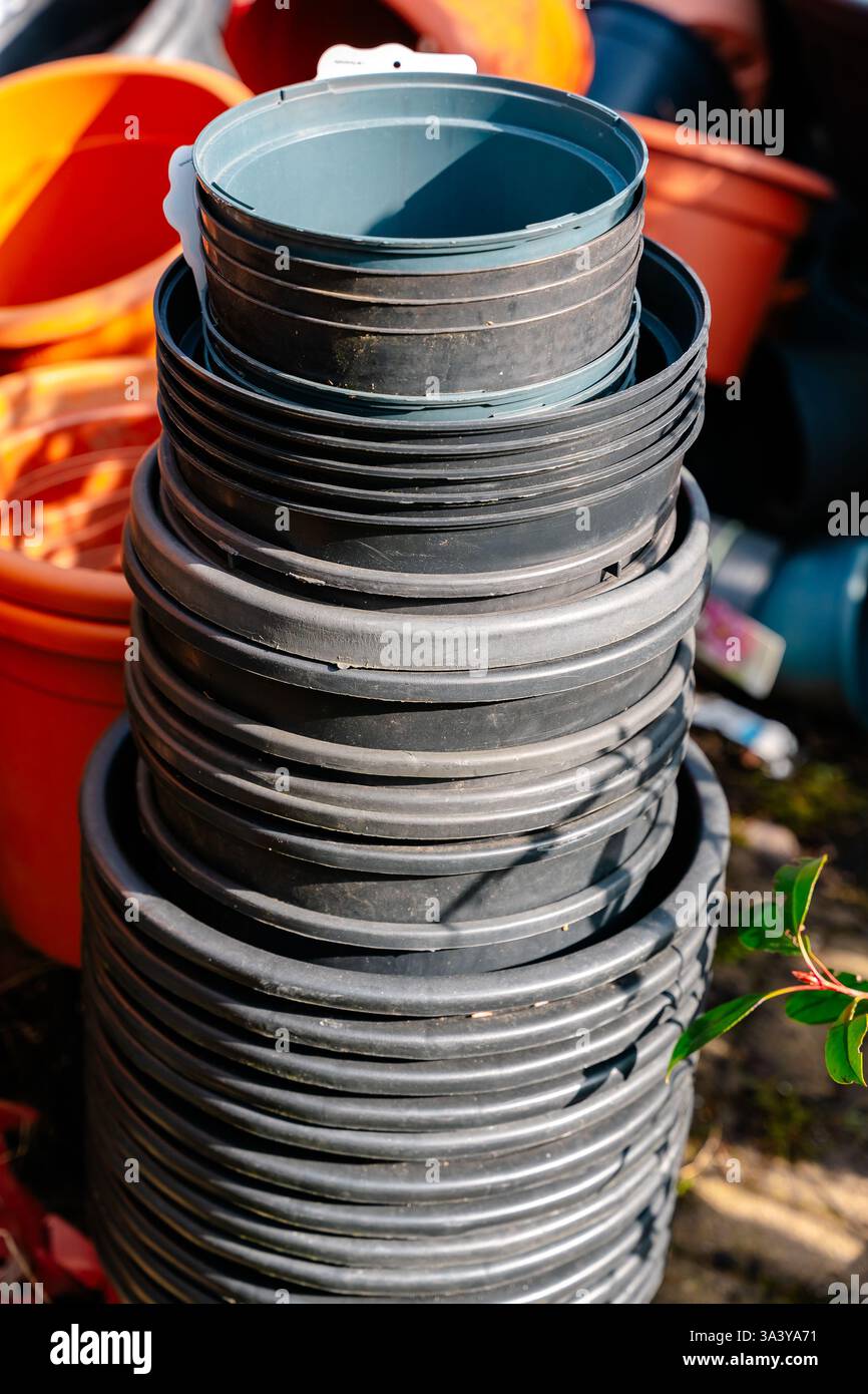 Stack of nested plastic plant pots in a garden setting. The pots are a ...