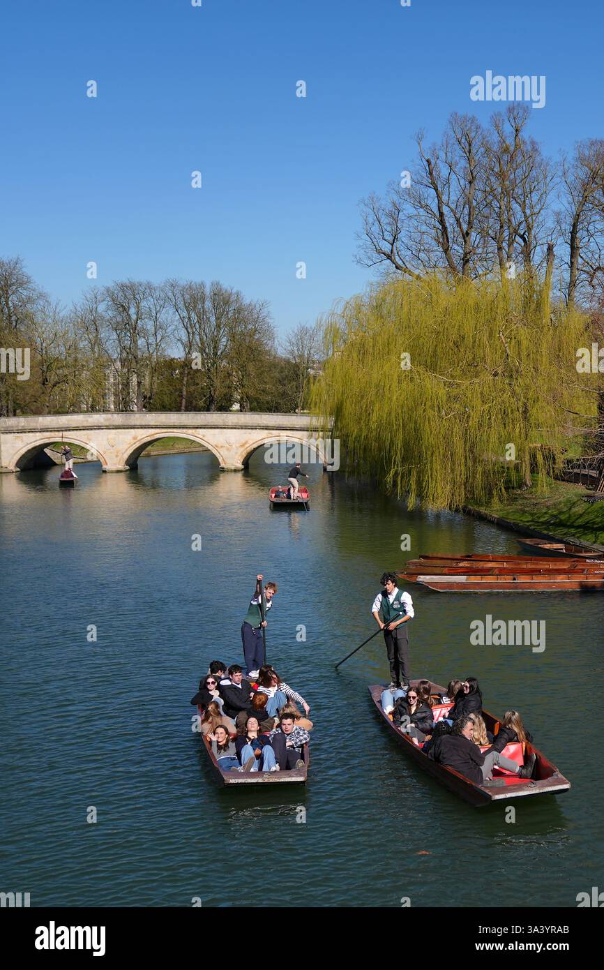People enjoy the sunshine as they punt along the River Cam in Cambridge ...