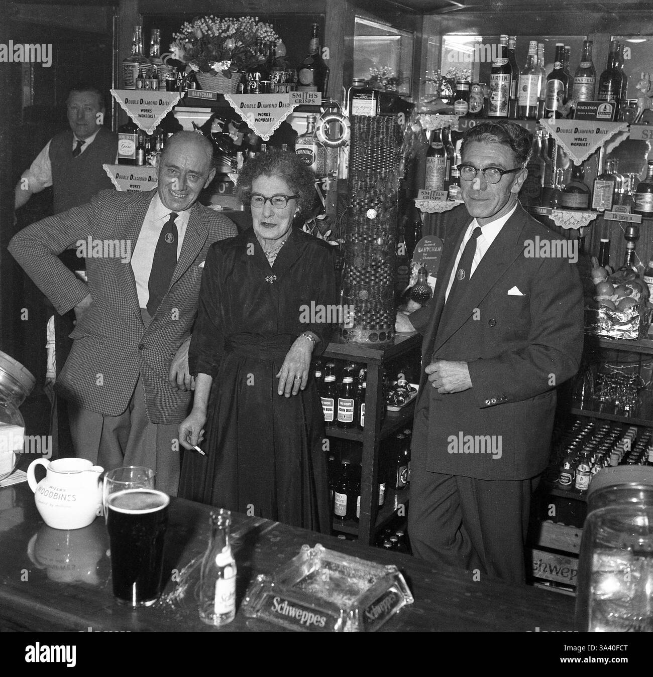 1950s, historical, at the bar of a pub, a landlord and land lady posing ...