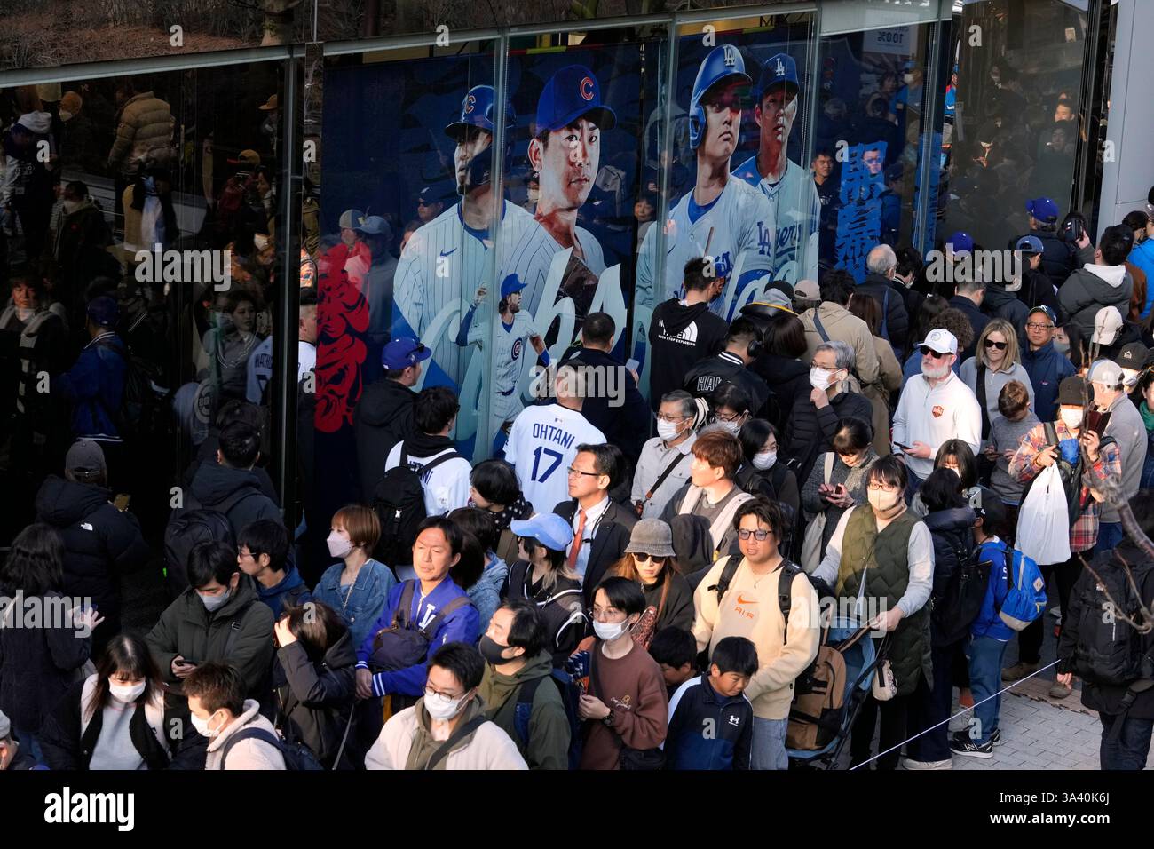 People wait in queue to enter an official shop before an MLB Japan Series baseball game between ...