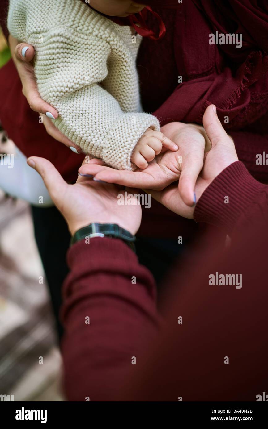 A touching close-up of a baby tiny hand reaching out to parents hands ...