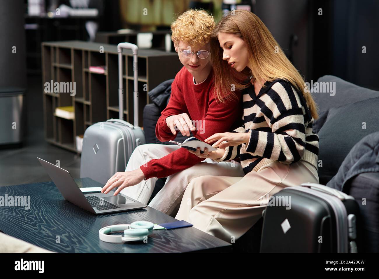 A young couple in a hotel lounge shares love while planning their ...