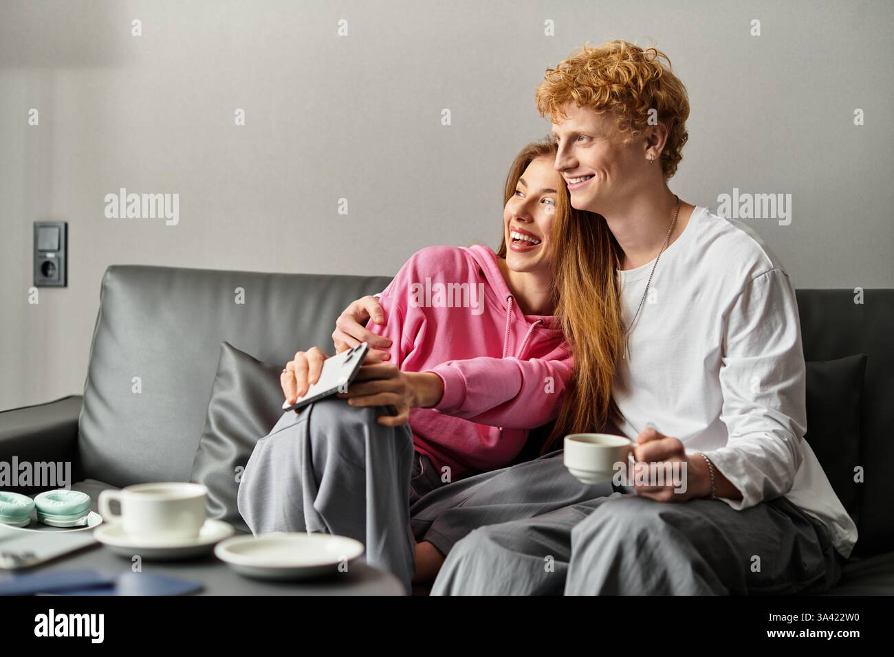 A young couple relaxes on a comfy couch, enjoying each others company ...