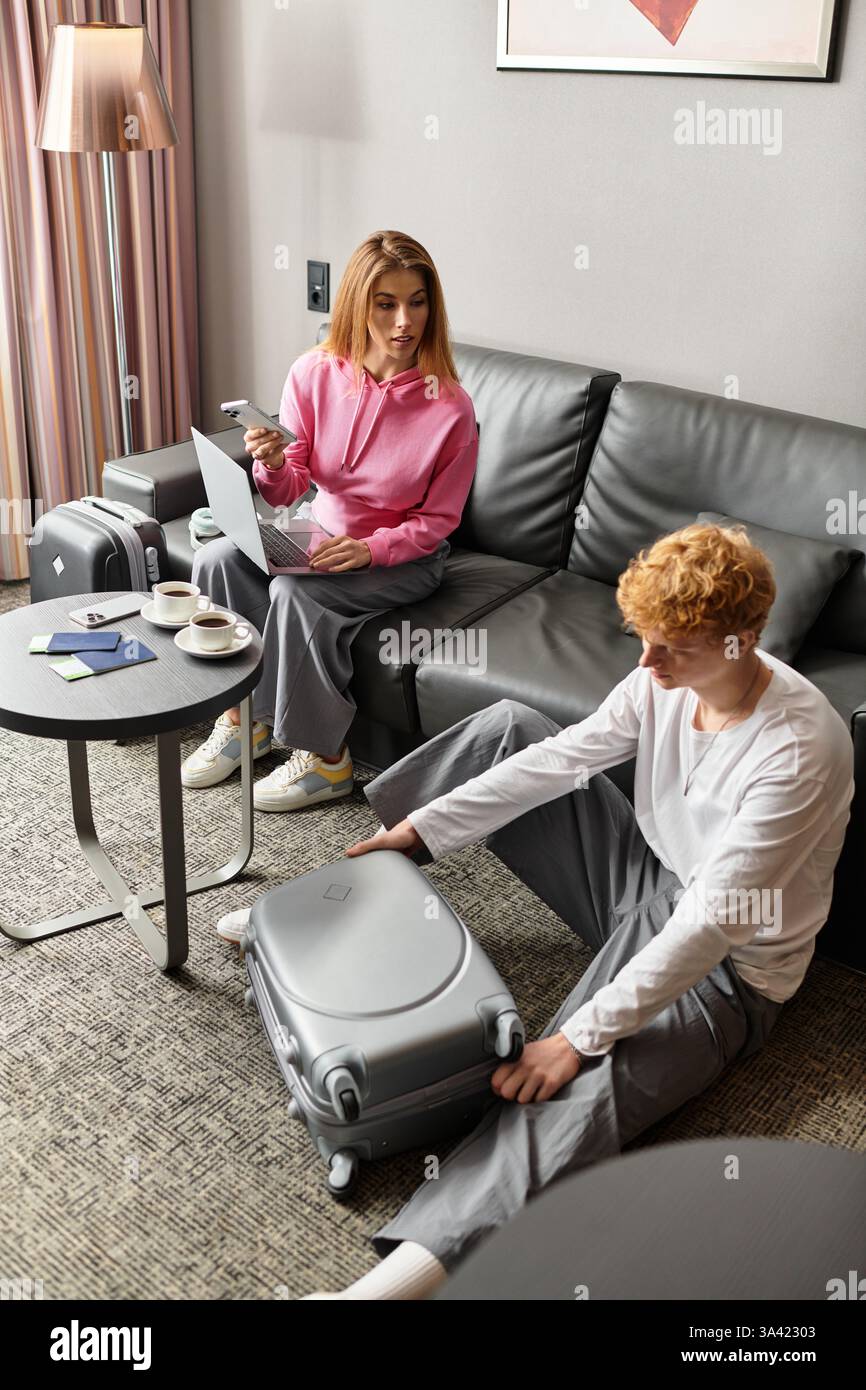 In a stylish hotel room, a young couple bonds over travel plans ...
