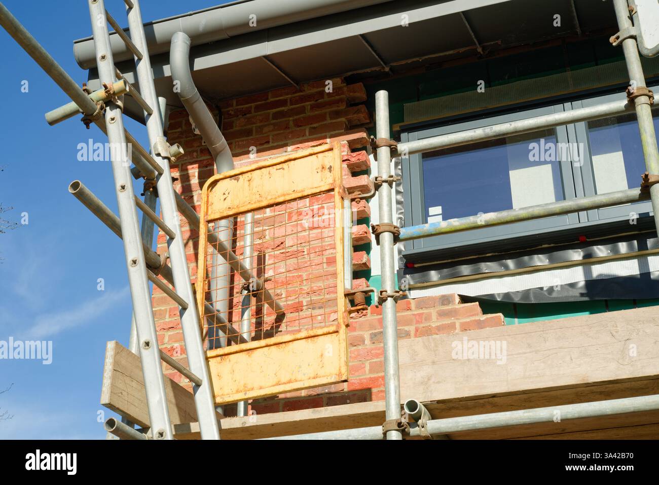 scaffolding, metal ladder and scaffold boards and a gate. All against a ...
