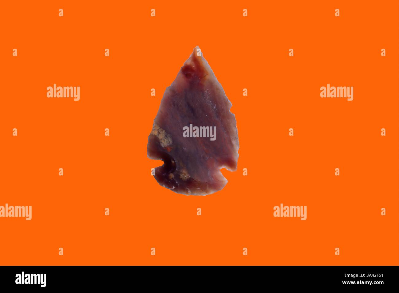 Handmade stone flint Arrow point isolated over an orange background ...