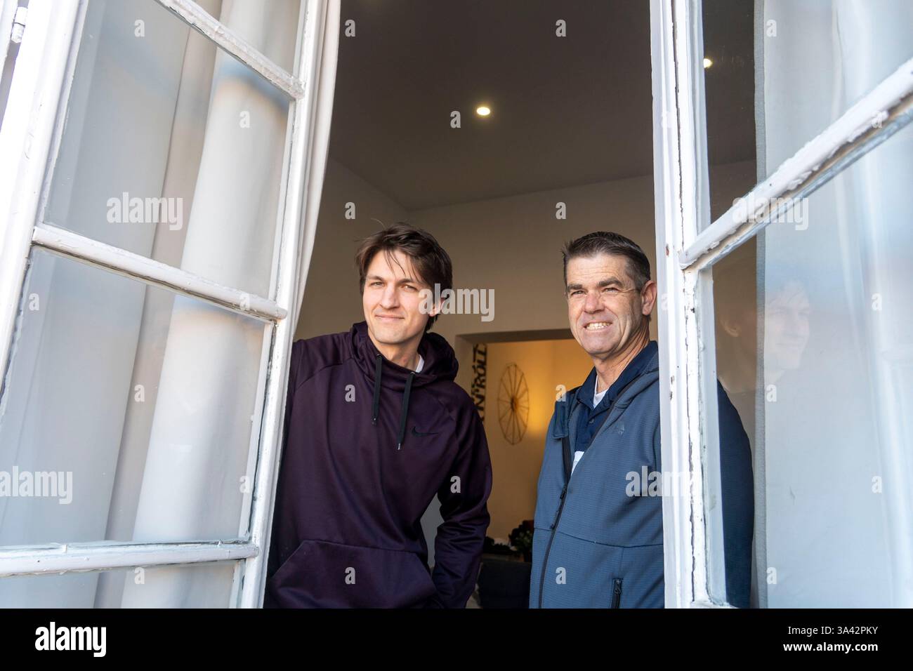 Two men stand next to each other by an open window Stock Photo - Alamy
