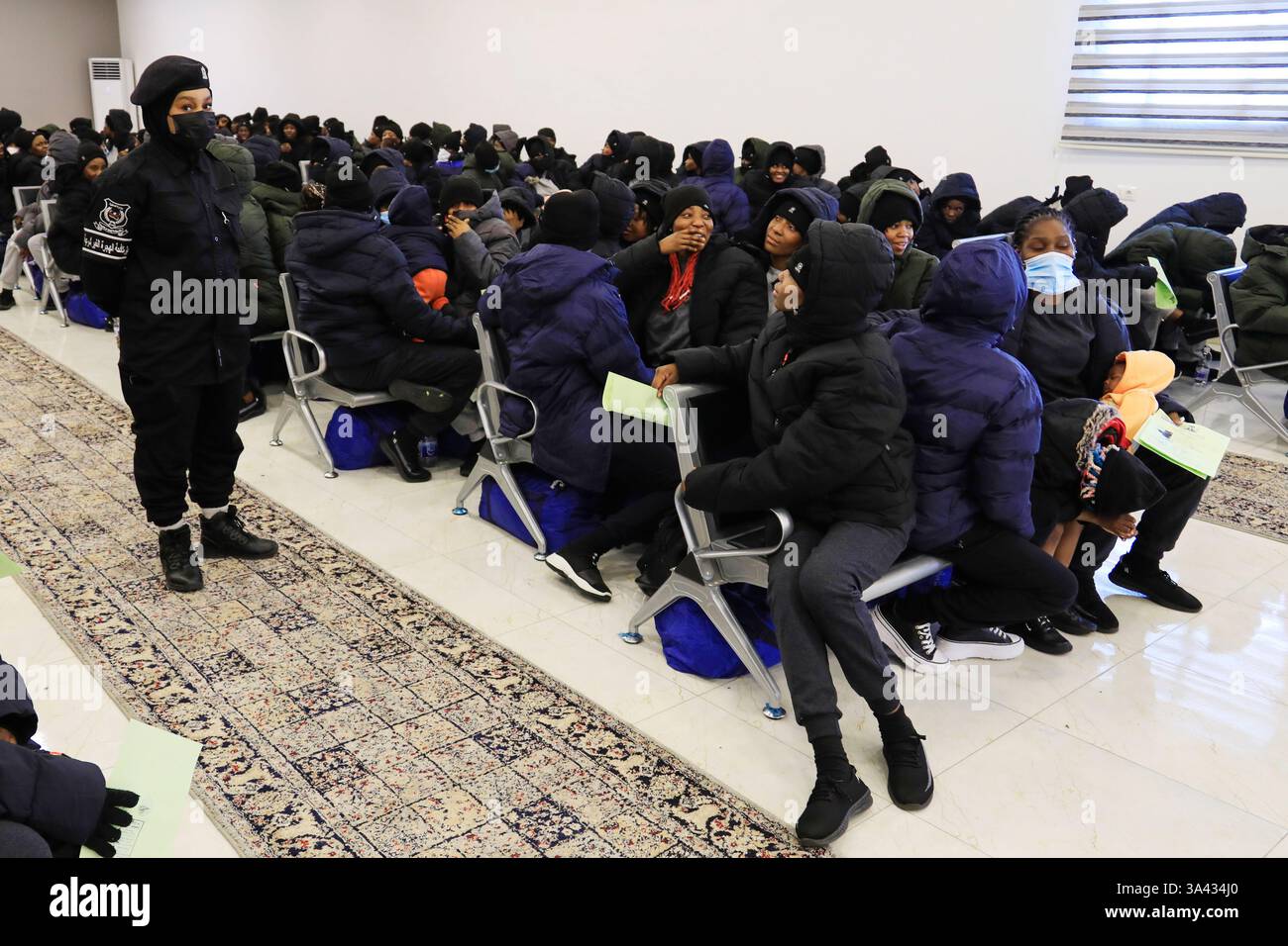 A Libyan police officer stands guard as Nigerian migrants wait before ...