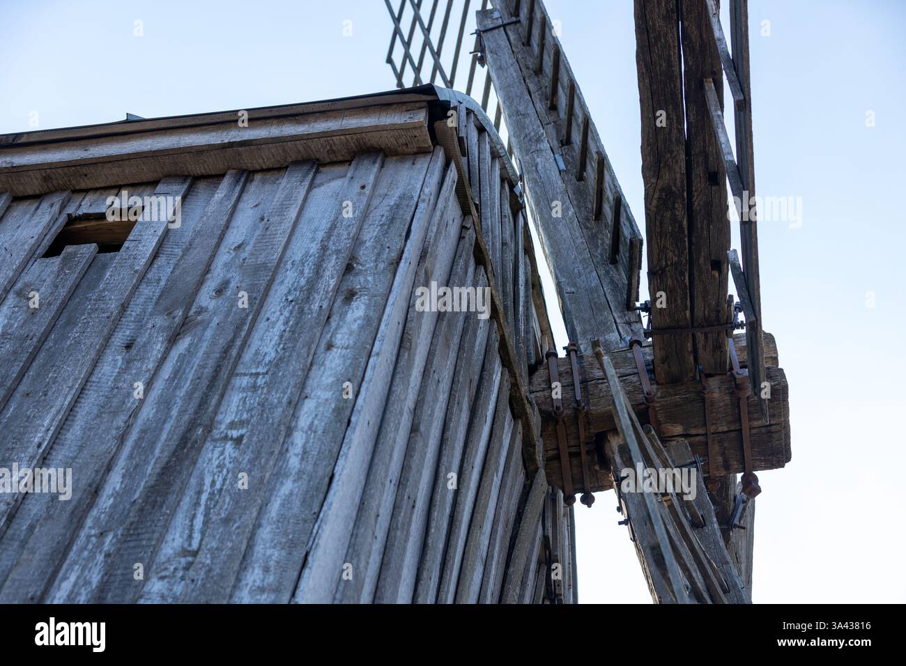 Wooden windmill blades rotating against a blue sky, showing weathered ...