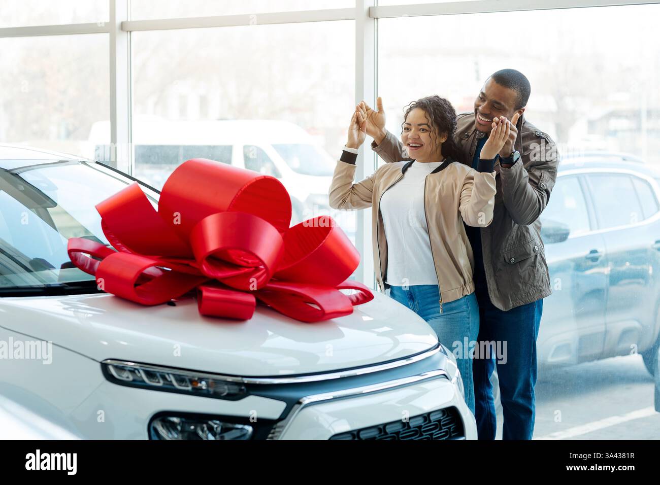 Excitement grows as a young couple celebrates their new car purchase at ...