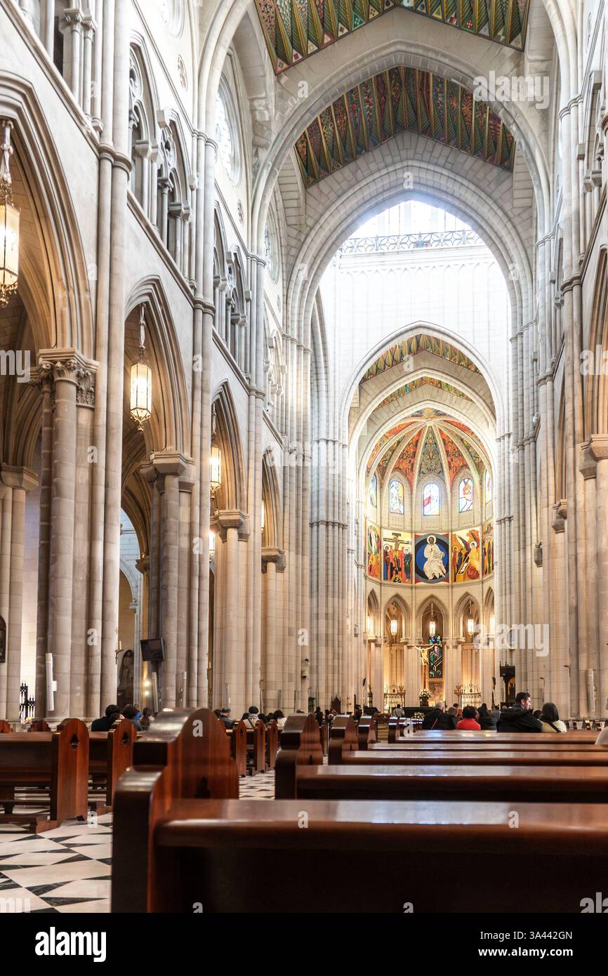 Inside a large church, you can see rows of wooden benches arranged ...
