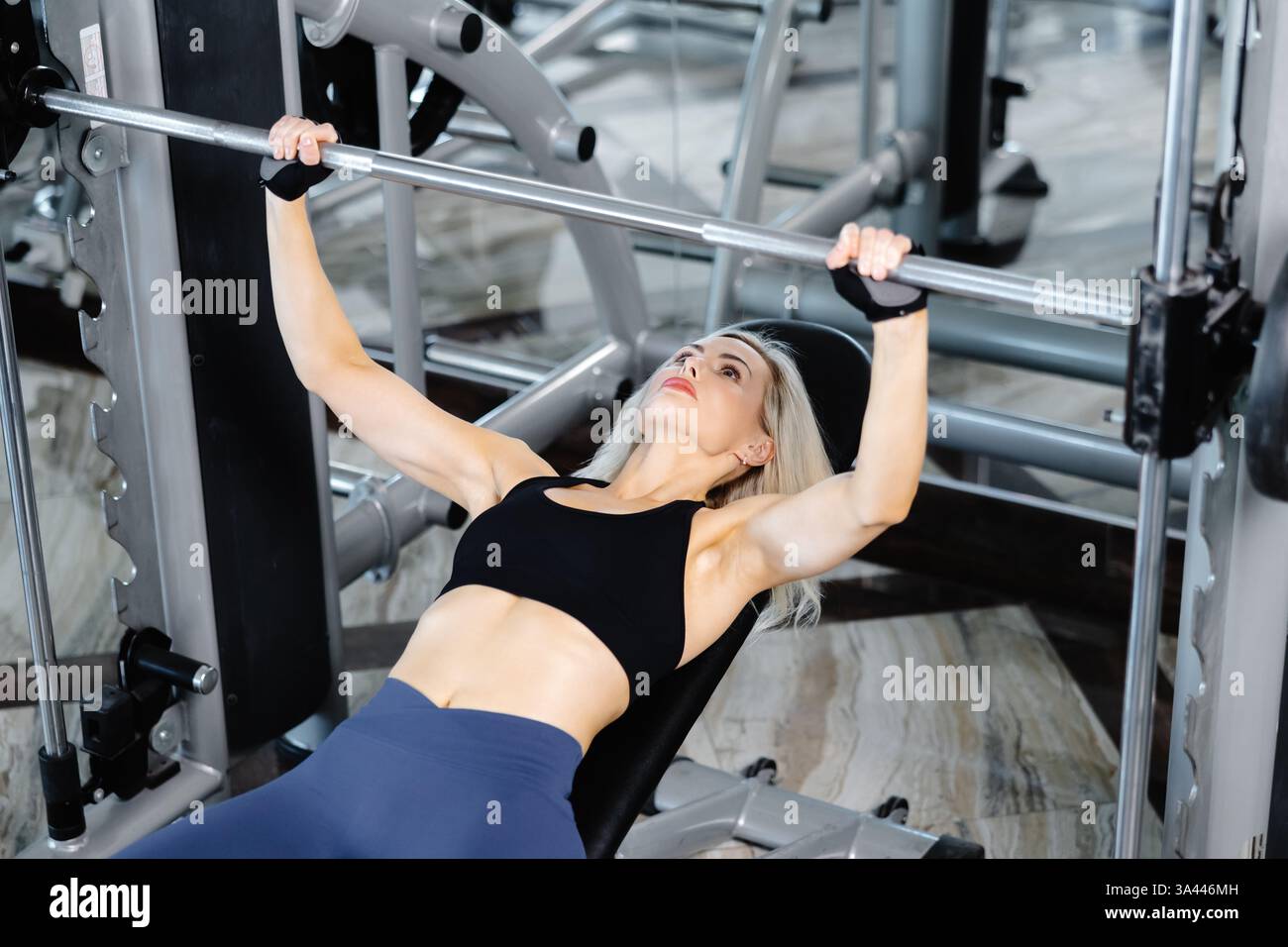 Strong woman bodybuilder executing a bench press with a barbell in a ...