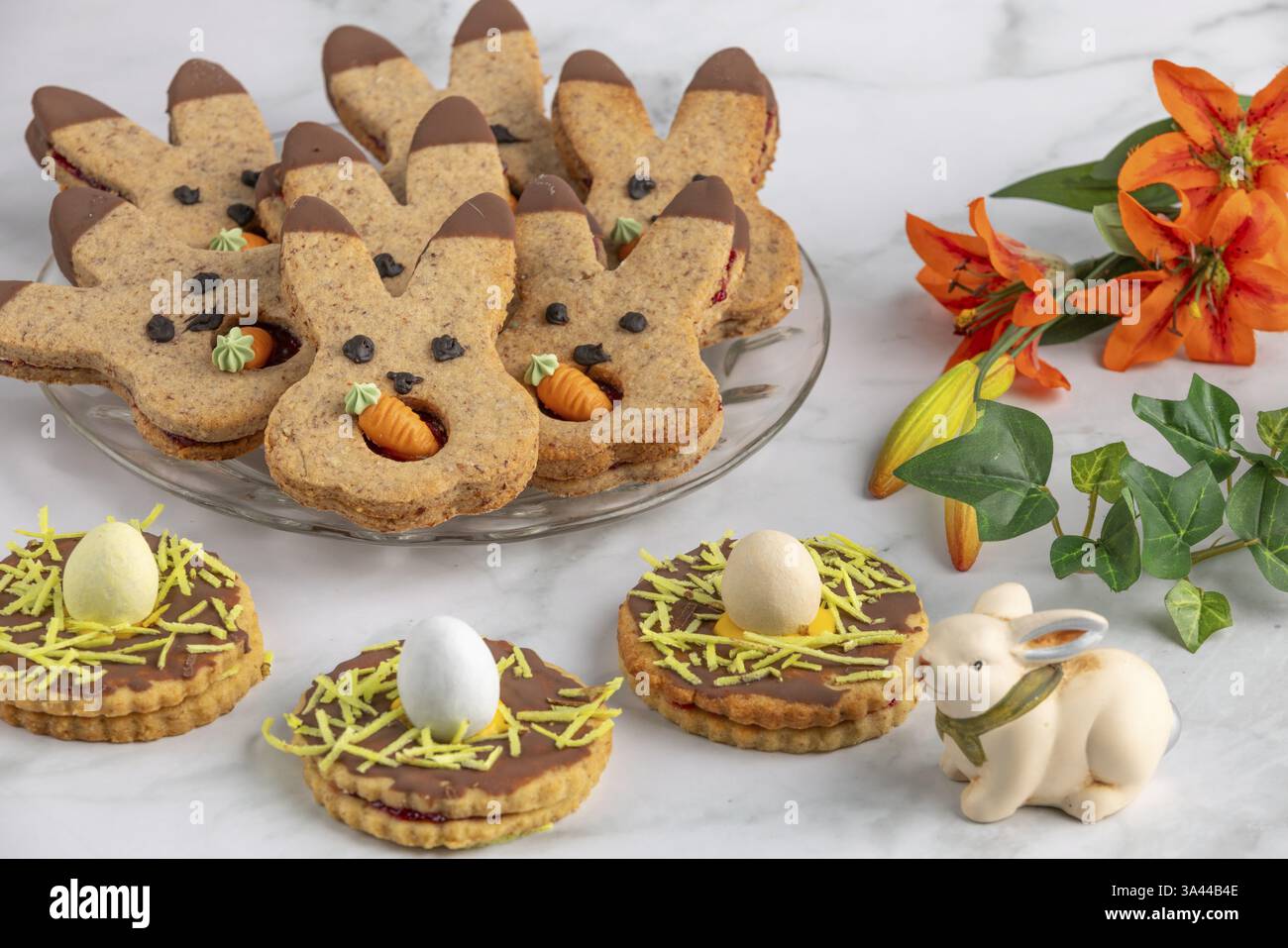 Bunny biscuits with carrots and egg decoration next to orange flowers ...
