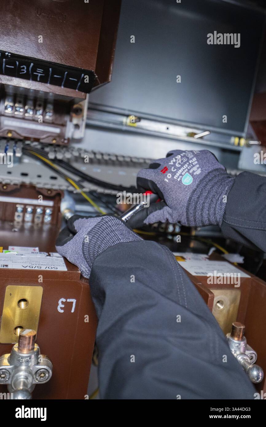 A technician uses tools for maintenance work inside a switch box ...