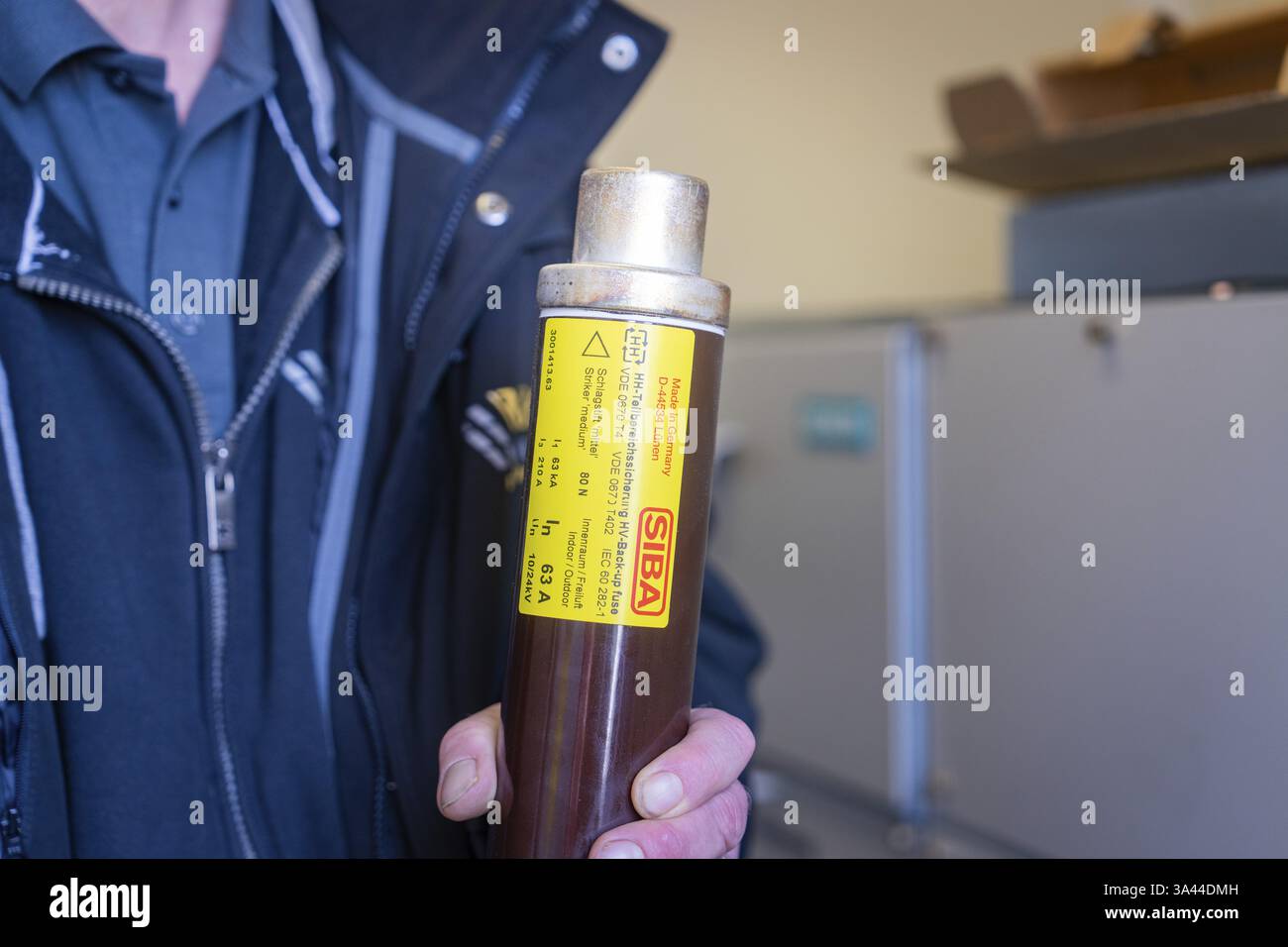 Person holding a fuse with SIBA label focussed on electrical safety ...
