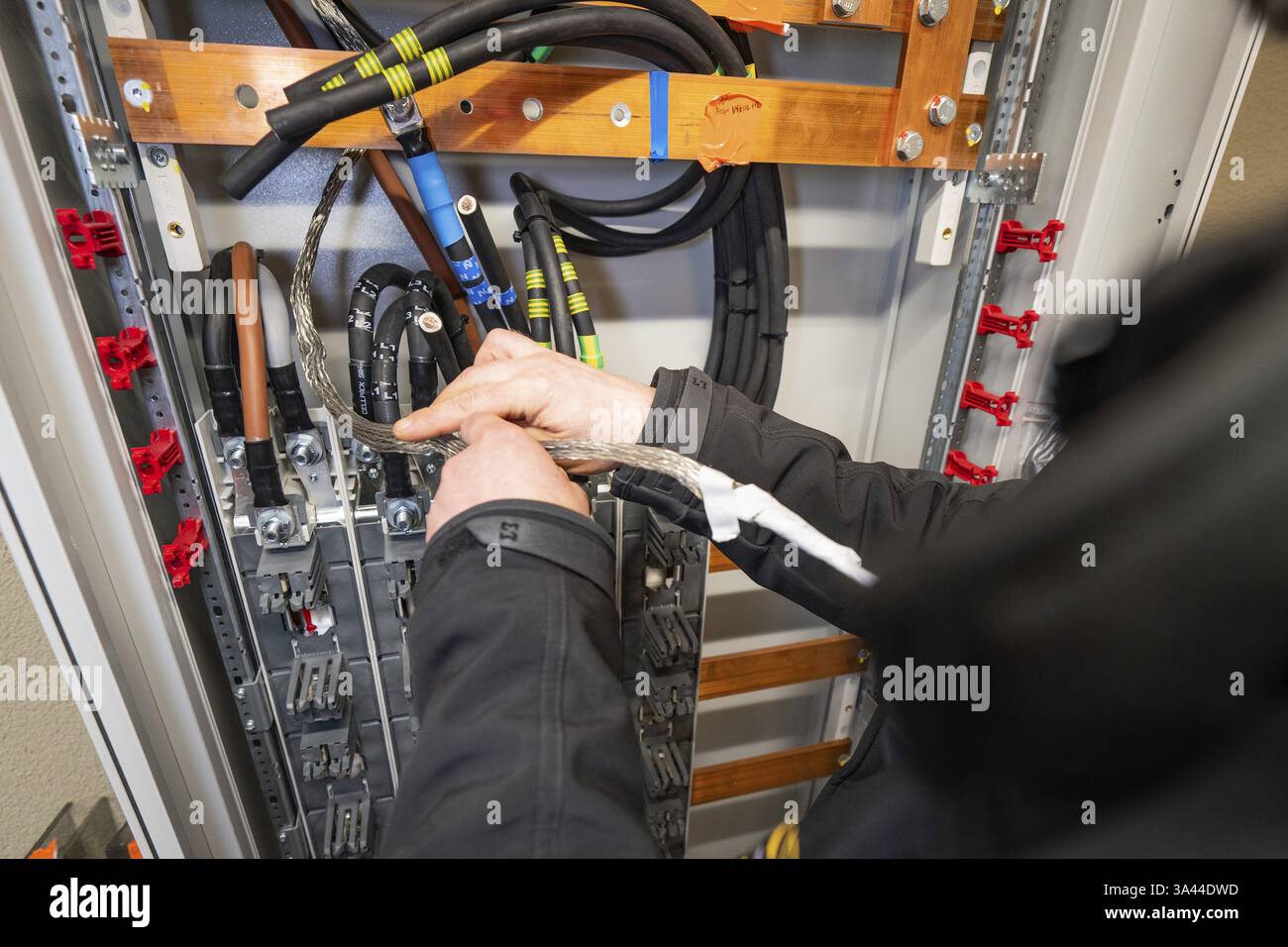 Electrician working on an open power box with visible cables and ...