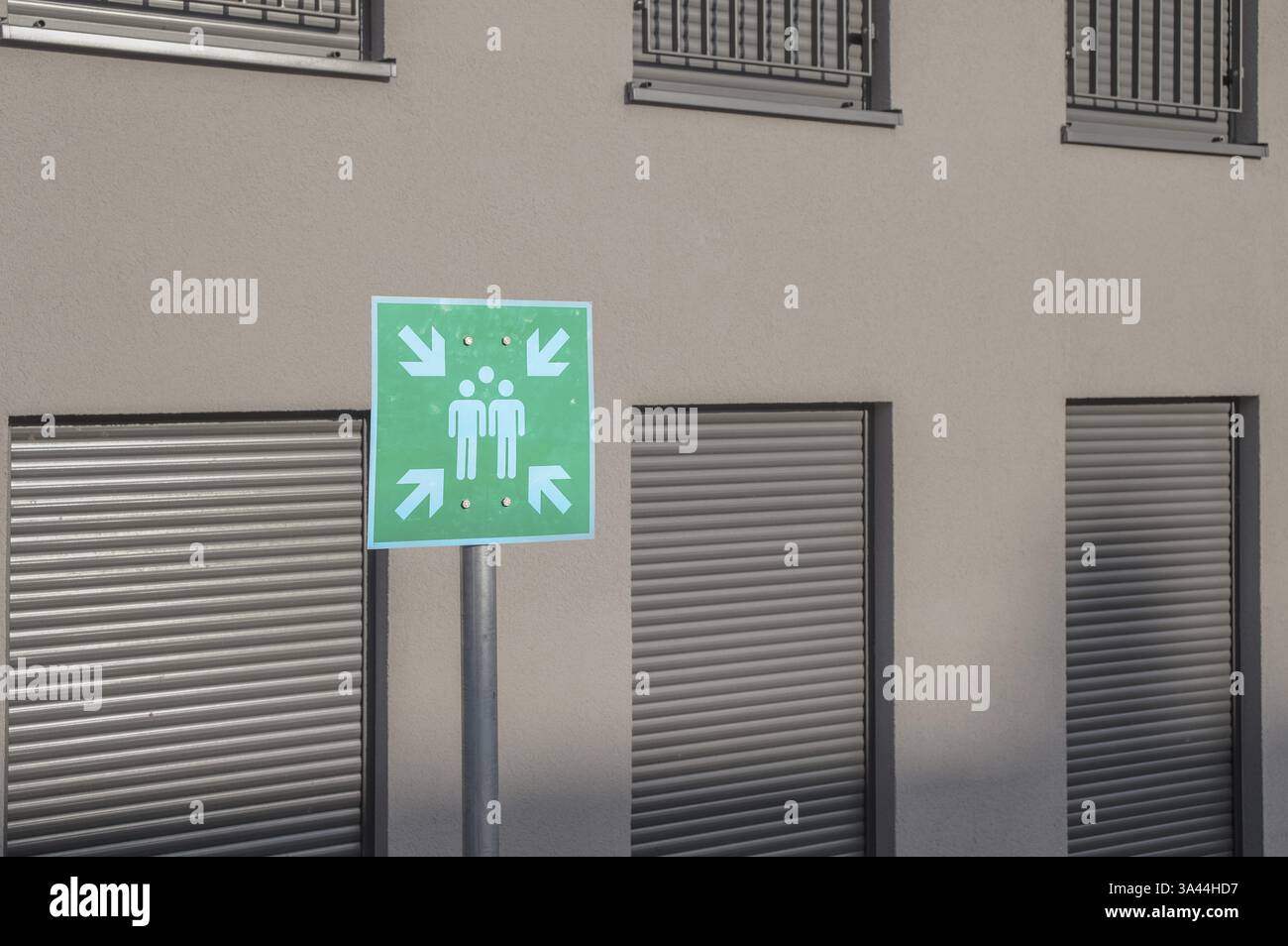 Green assembly point sign indicating escape route and meeting place for ...