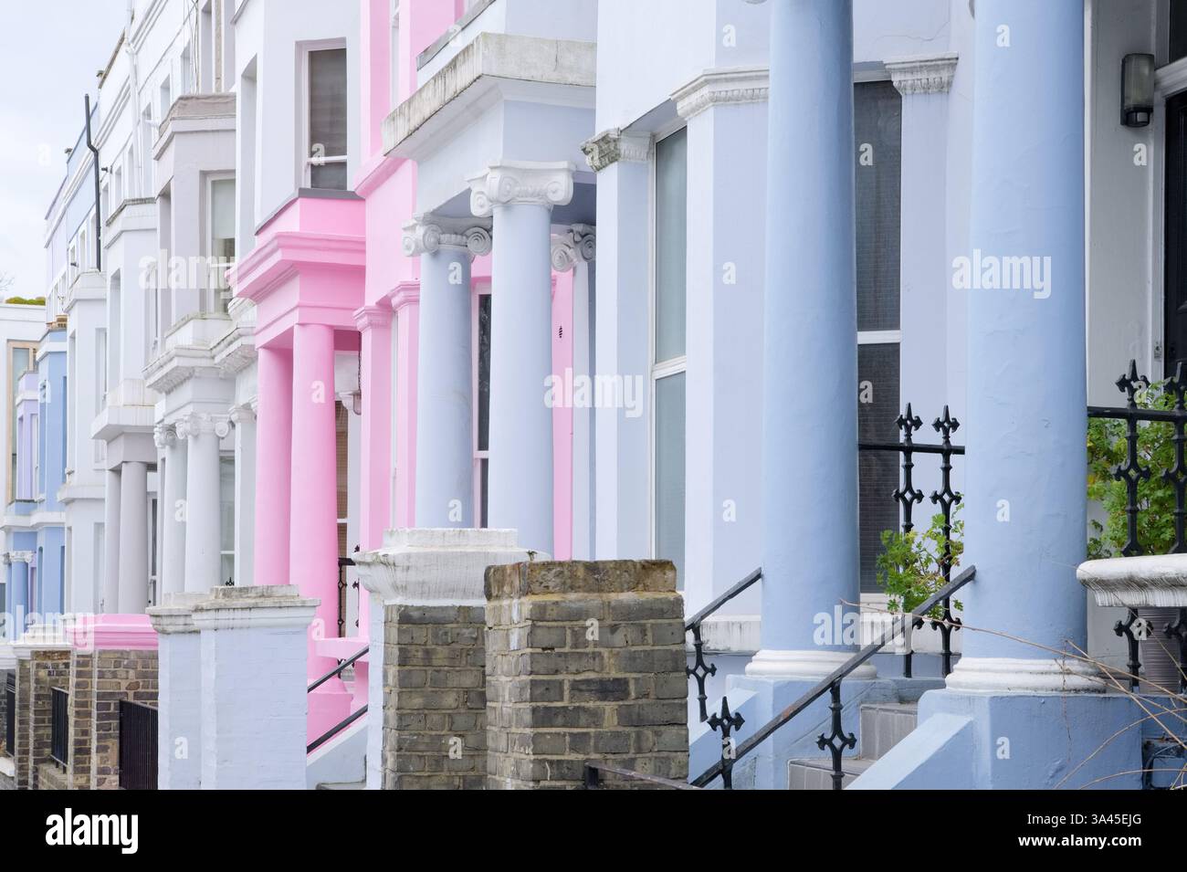 Bay windows and porches with pillars on pastel coloured terraced houses ...