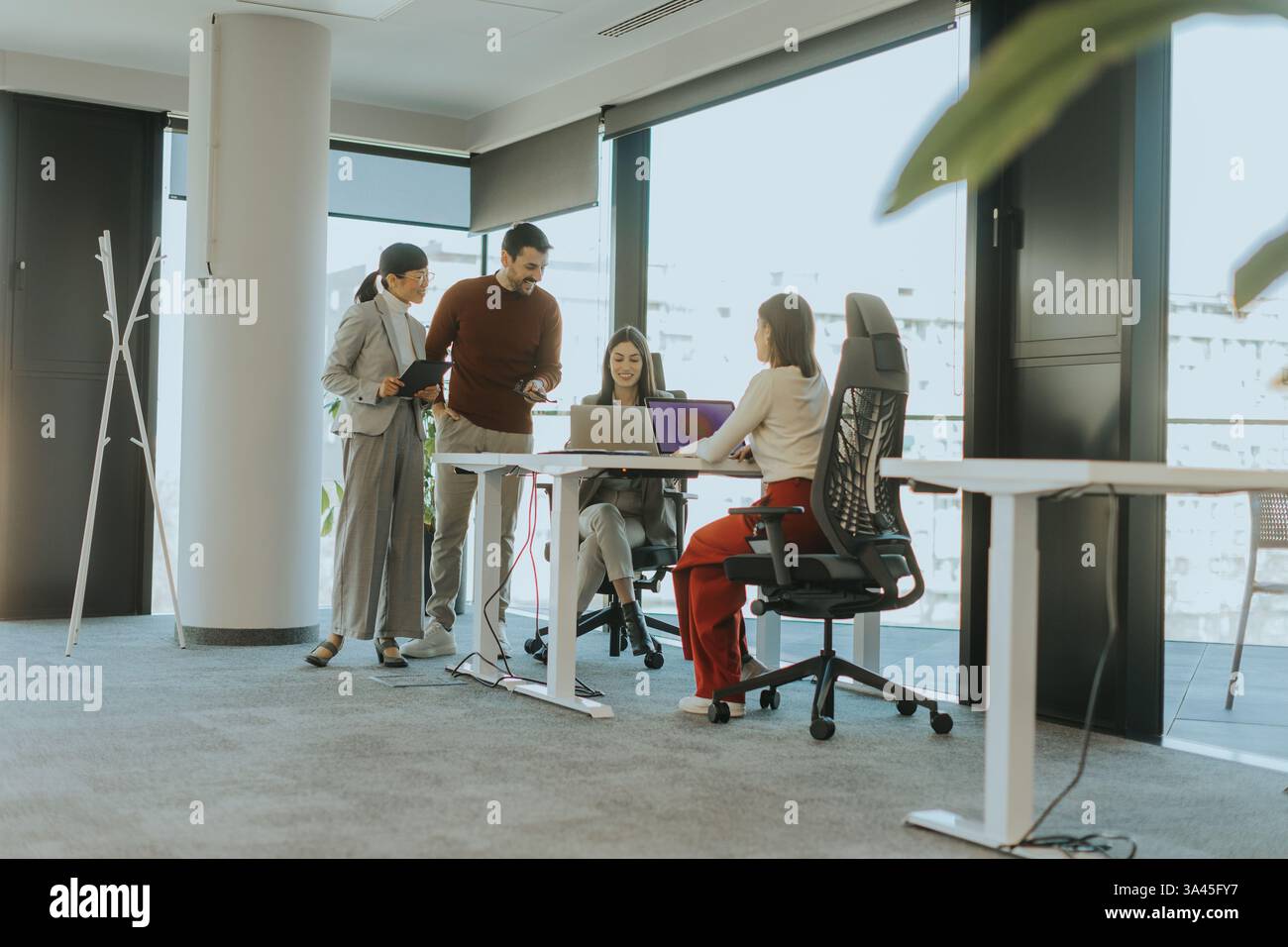 Four professionals engage in a dynamic discussion around laptops in a ...