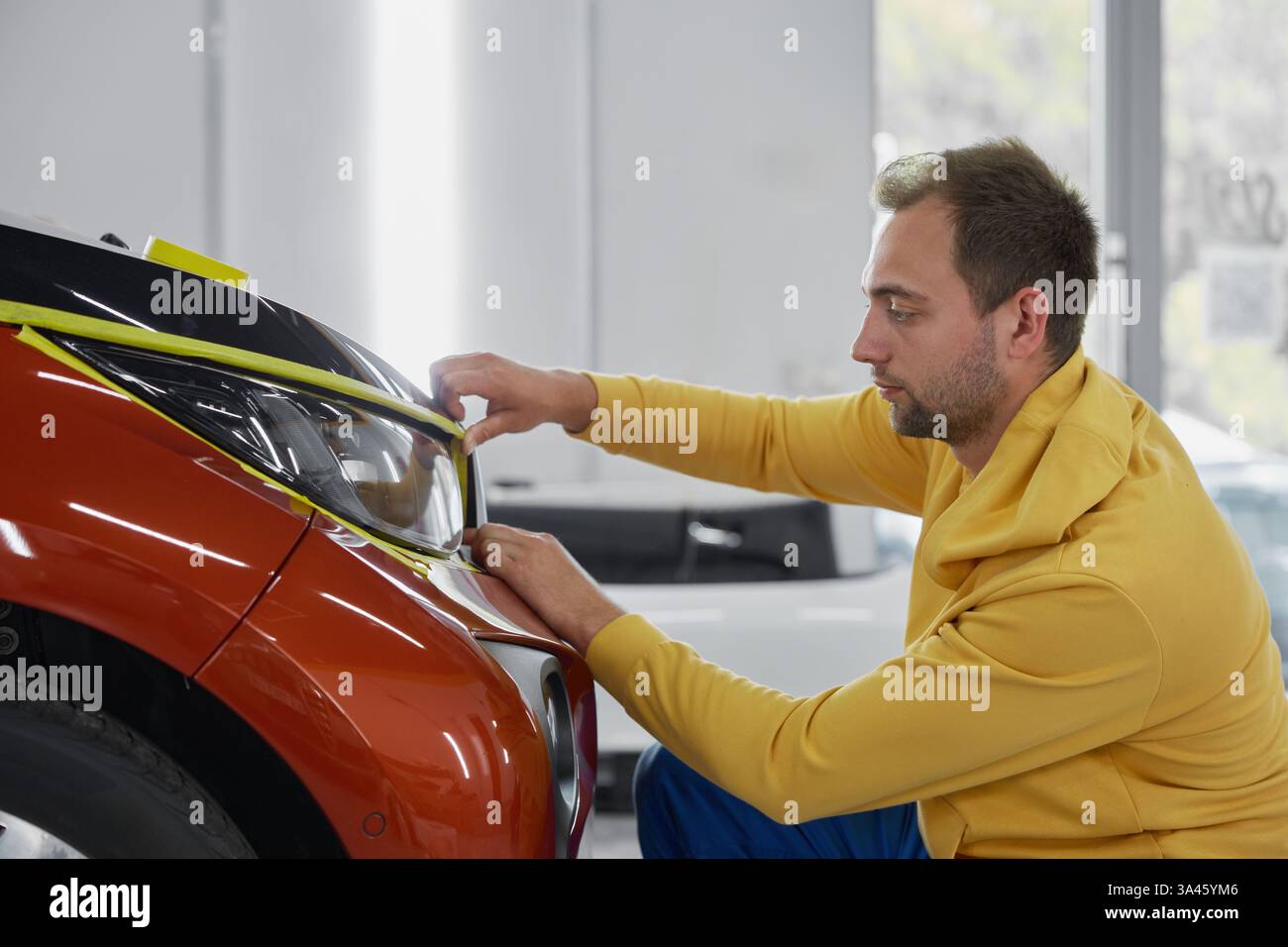 Man worker using masking tape to protect painted parts of body near ...