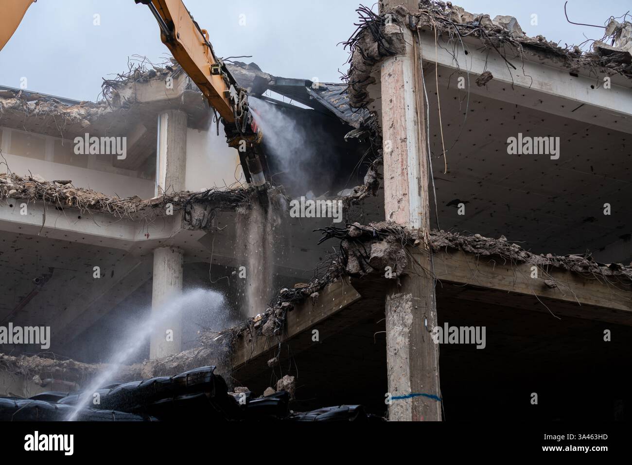 Heavy machinery is engaged in the controlled demolition of a concrete ...