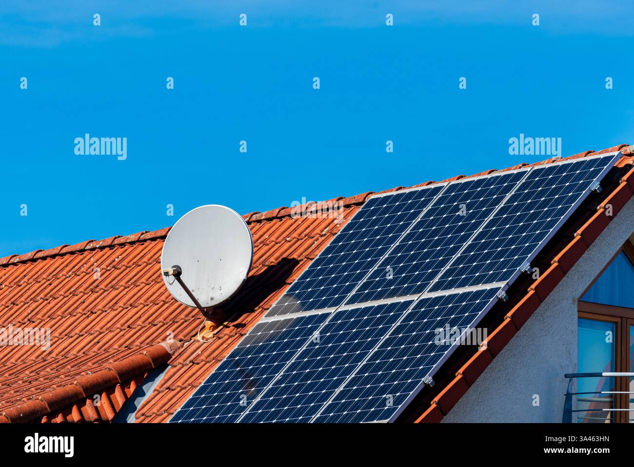 A rooftop features several solar panels alongside a satellite dish ...