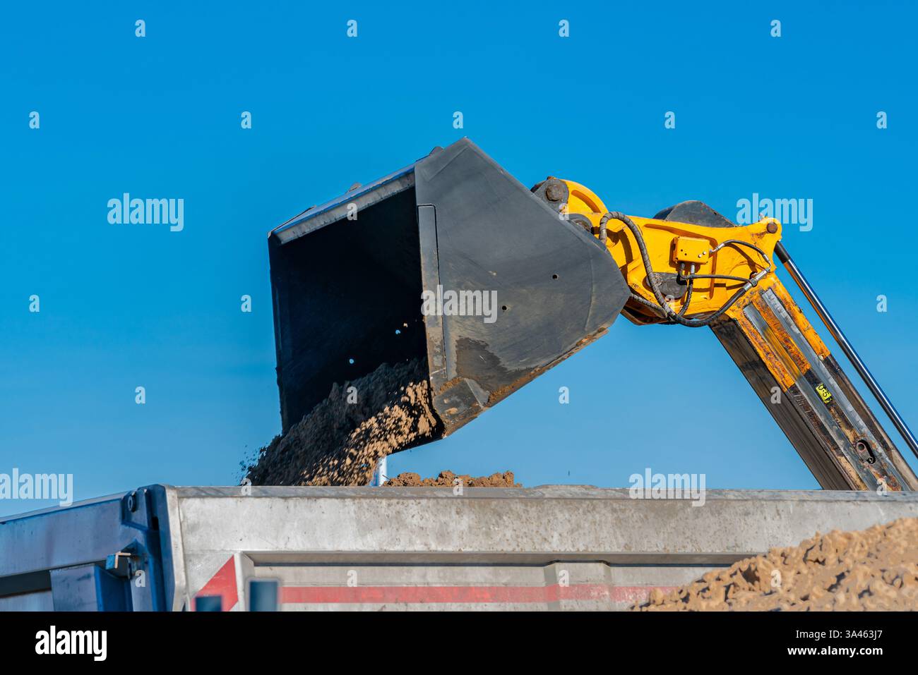 A large piece of construction equipment is actively dumping soil into a ...