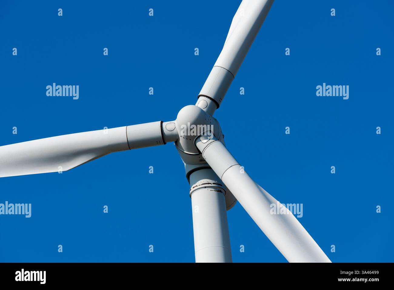 Close view of a wind turbine's blades rotating against a bright blue ...