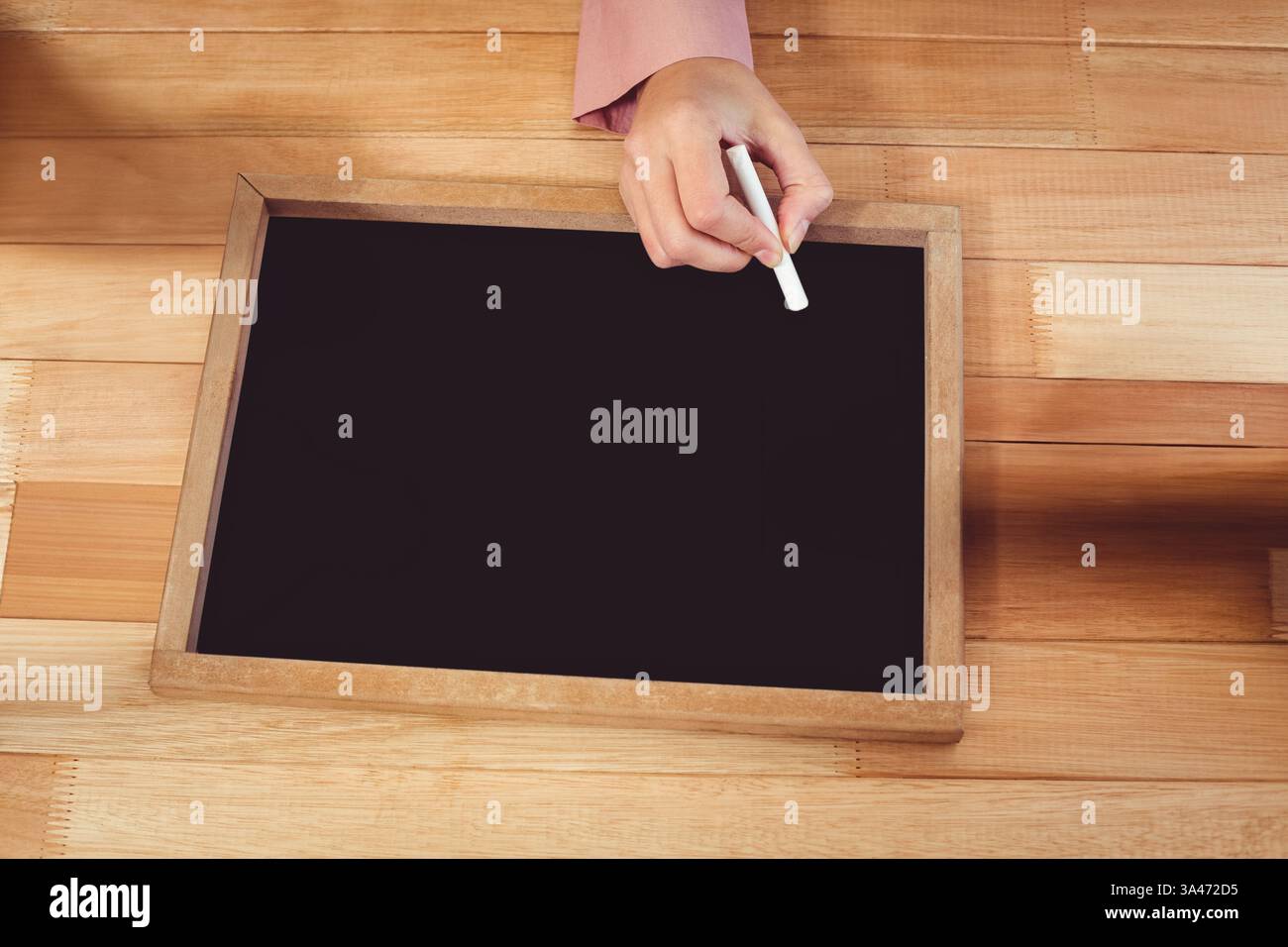 Hand holding chalk writing on small blackboard on wooden desk, copy ...