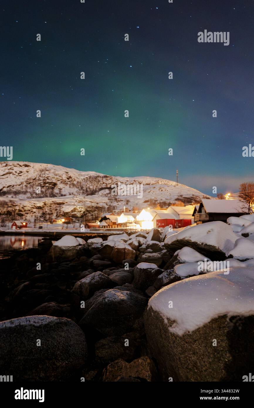Northern lights over cabins on arctic beach in Ersfjord near Tromso ...