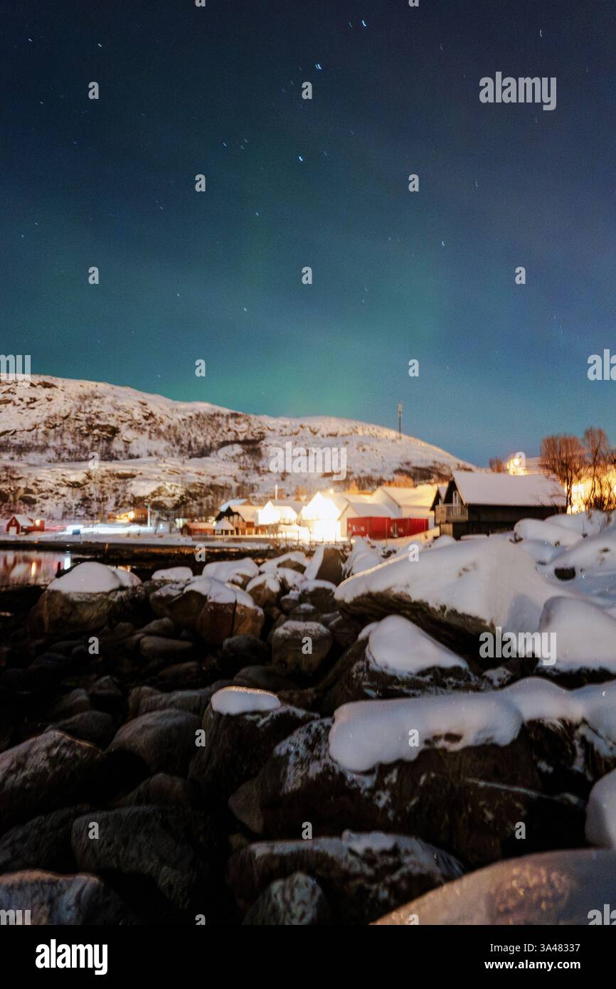 Aurora borealis over cabins on arctic beach in Ersfjord near Tromso ...