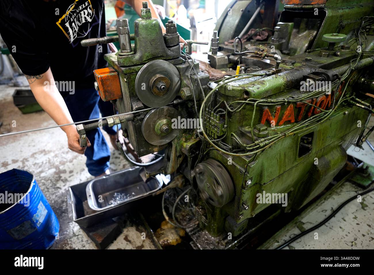 A worker feeds steel wire to machines making screws at Komar Screw Corp ...