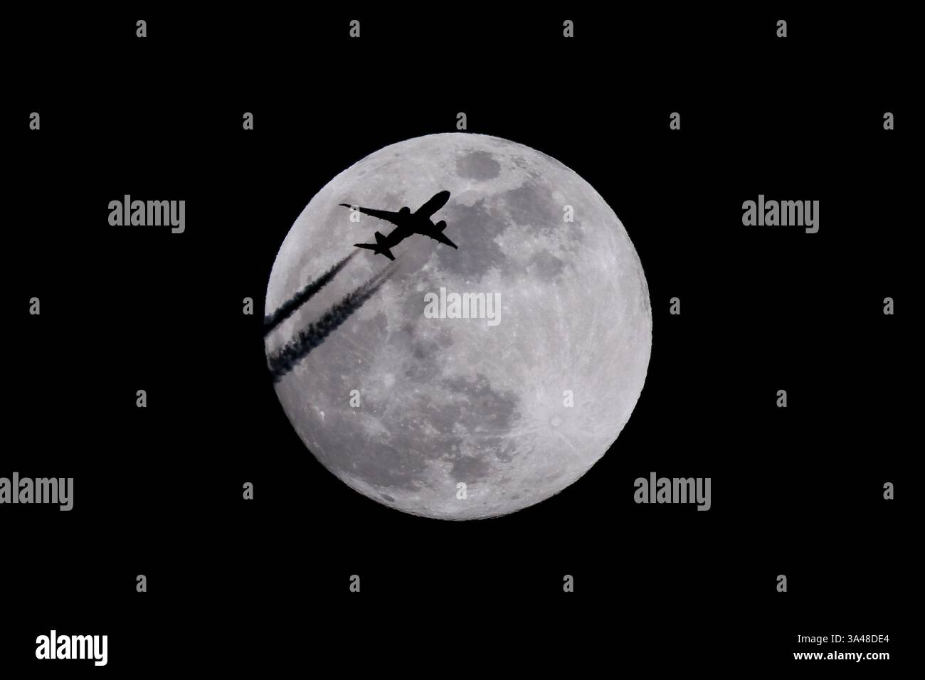 Plane flying in the night sky with the moon in the background. Airliner ...