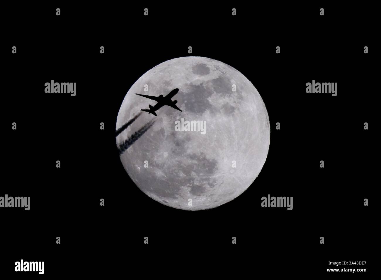 Plane flying in the night sky with the moon in the background. Airliner ...