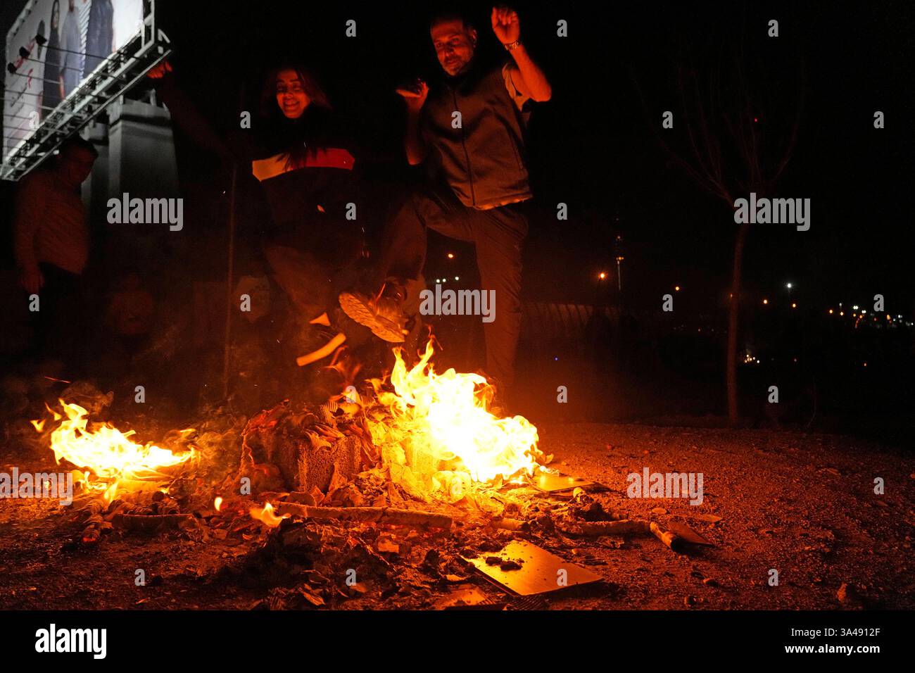 Iranians jump over a bonfire celebrating Chaharshanbe Souri, or ...