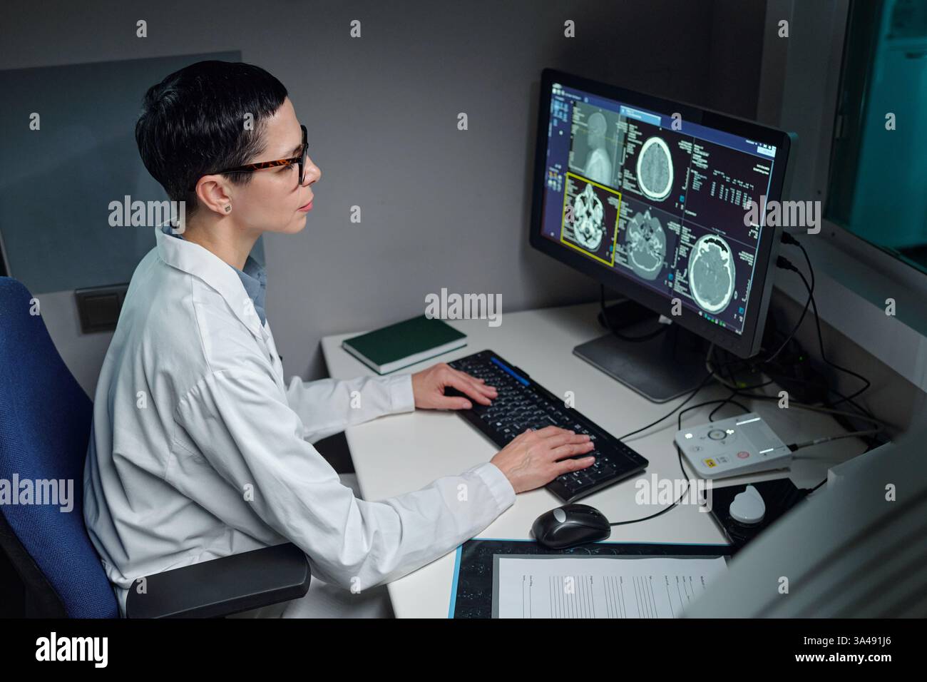 Medical professional analyzing brain scan images on computer screen in ...