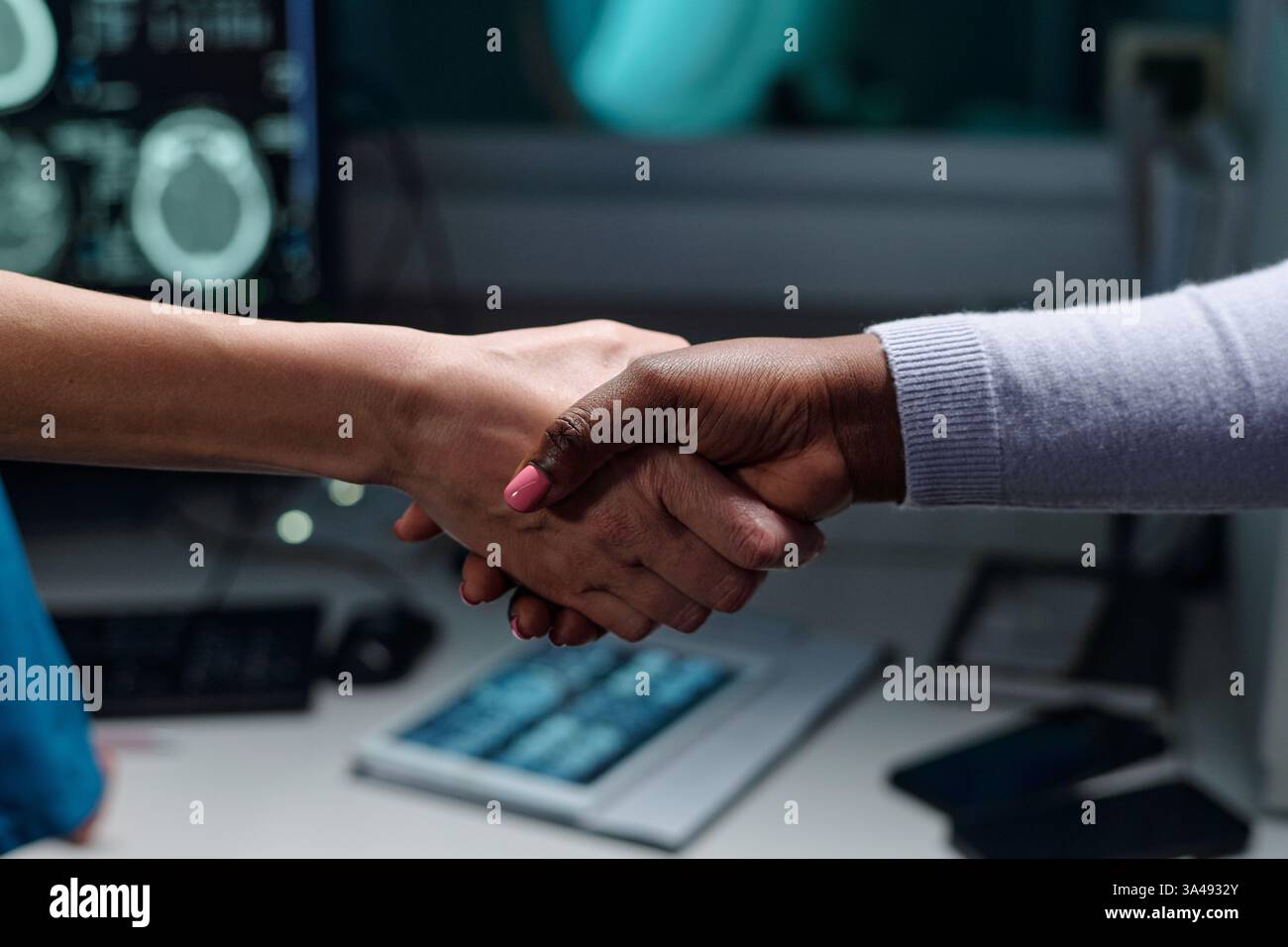 Two people of different races shaking hands, captured in a medical ...