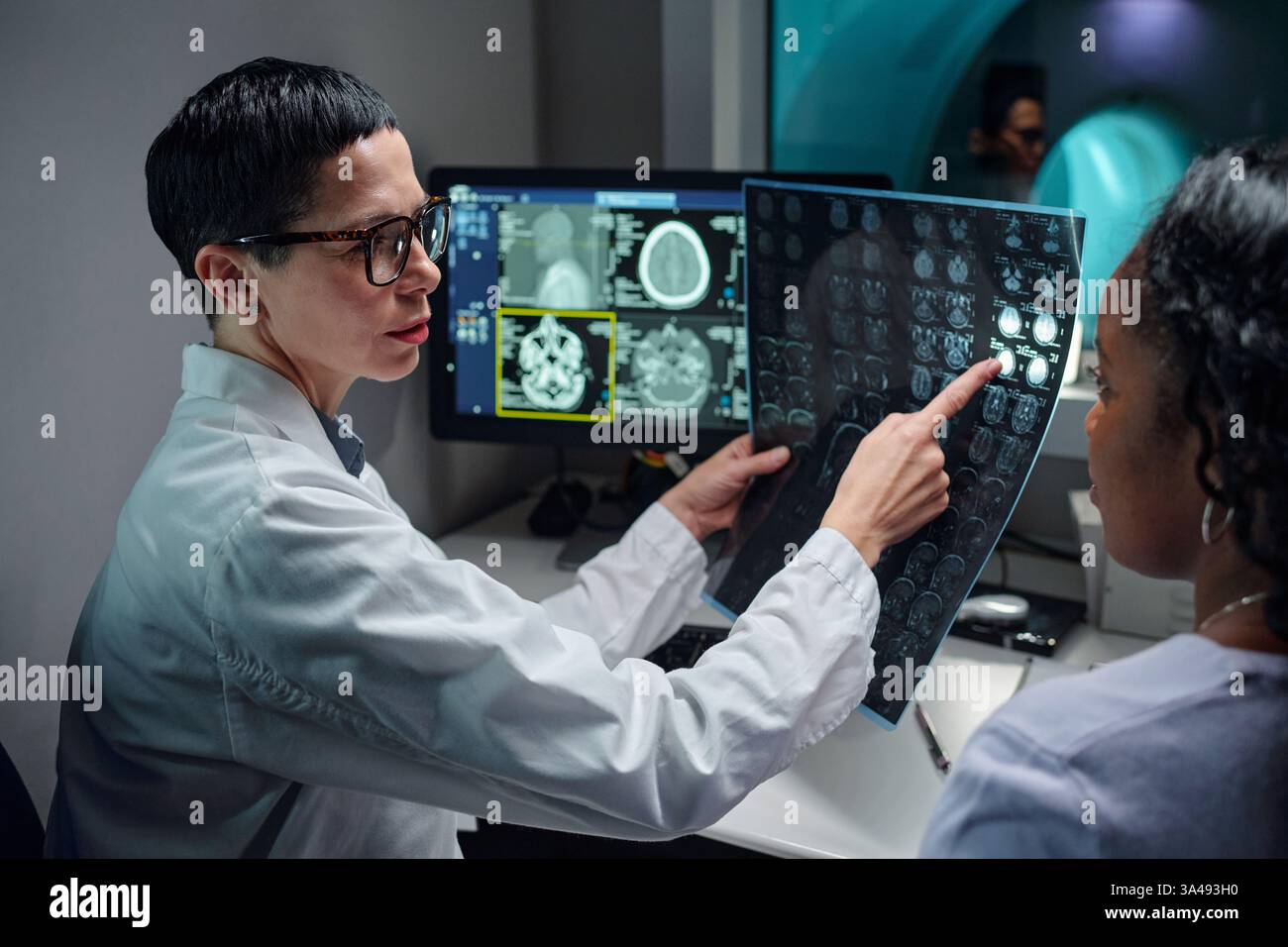 Doctor explaining MRI scan results to patient while using computer ...