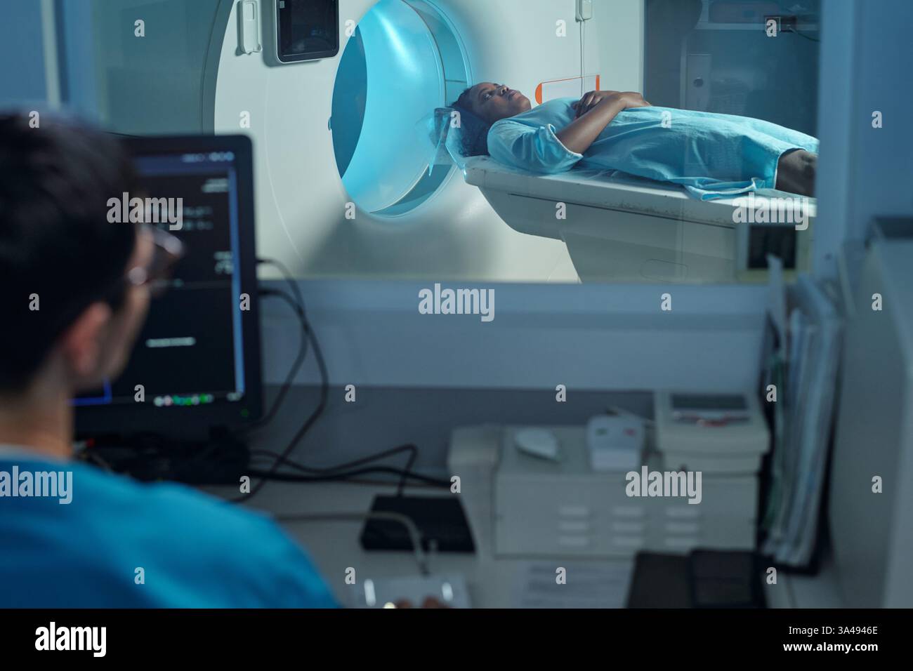 Patient lying inside MRI machine while medical professional monitors ...