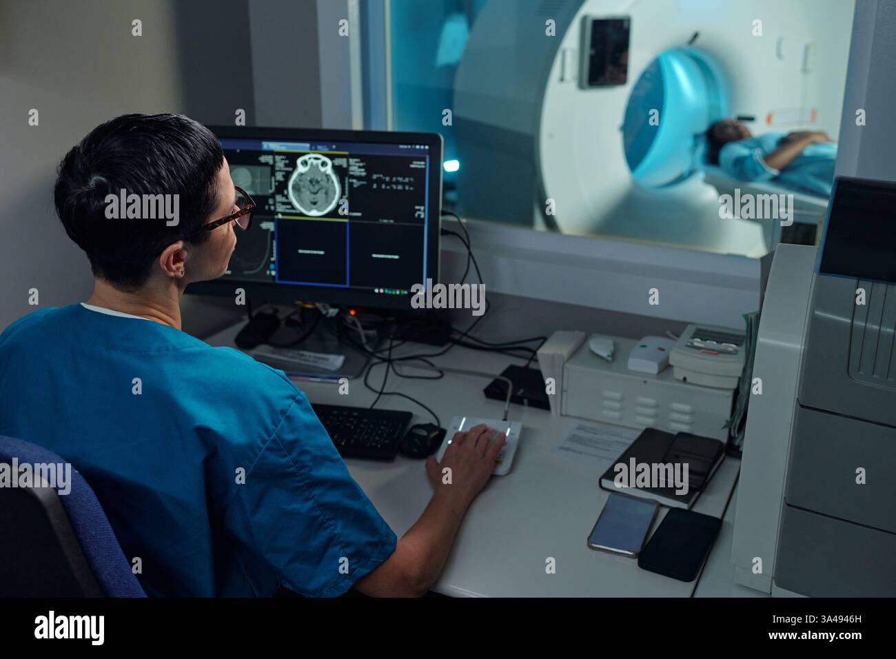 Medical professional in blue scrubs monitoring brain scans on computer ...