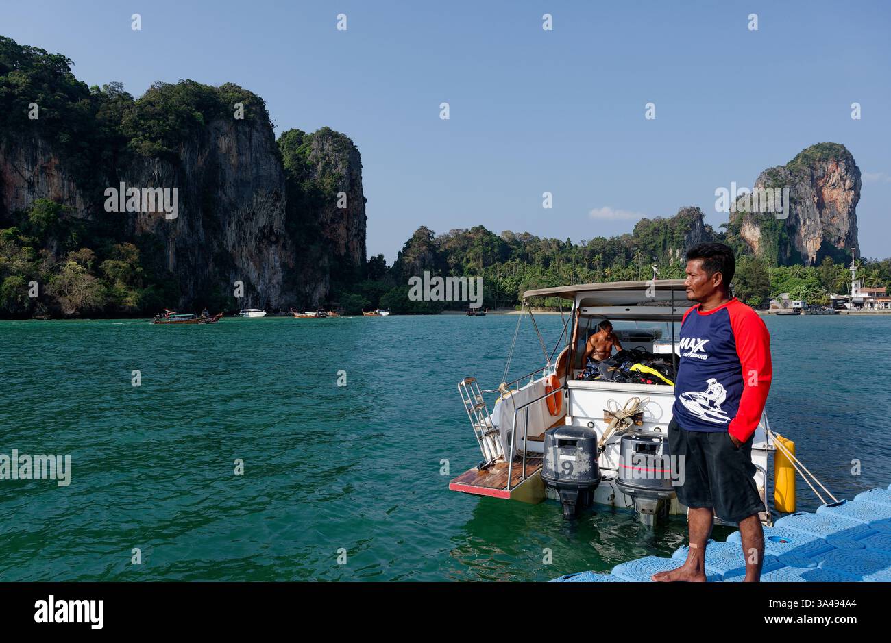 Local boat operator stands on the floating pier in Railay while gazing ...