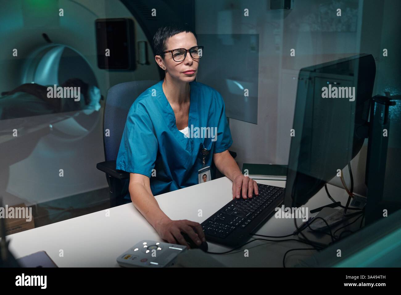 Medical professional in scrubs monitoring patient MRI scan in a ...