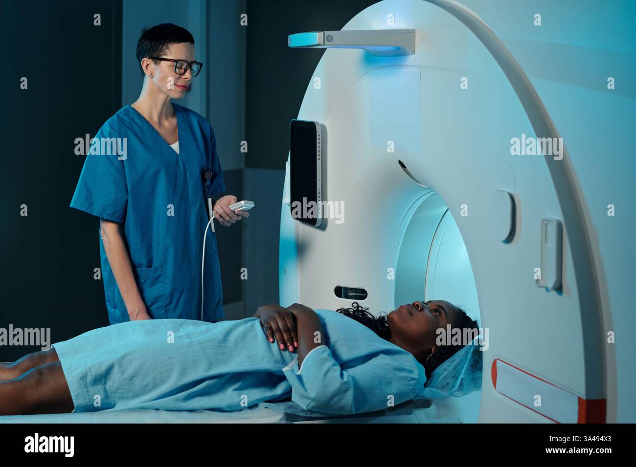 Medical professional wearing blue scrub assisting patient lying inside ...