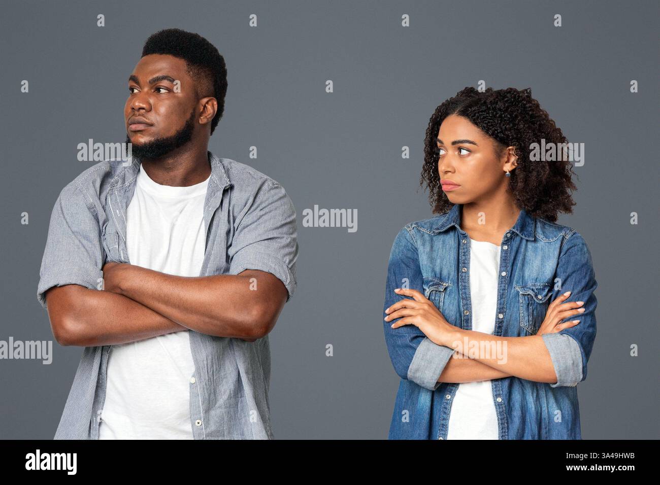 A couple stands apart with crossed arms, signaling tension Stock Photo ...