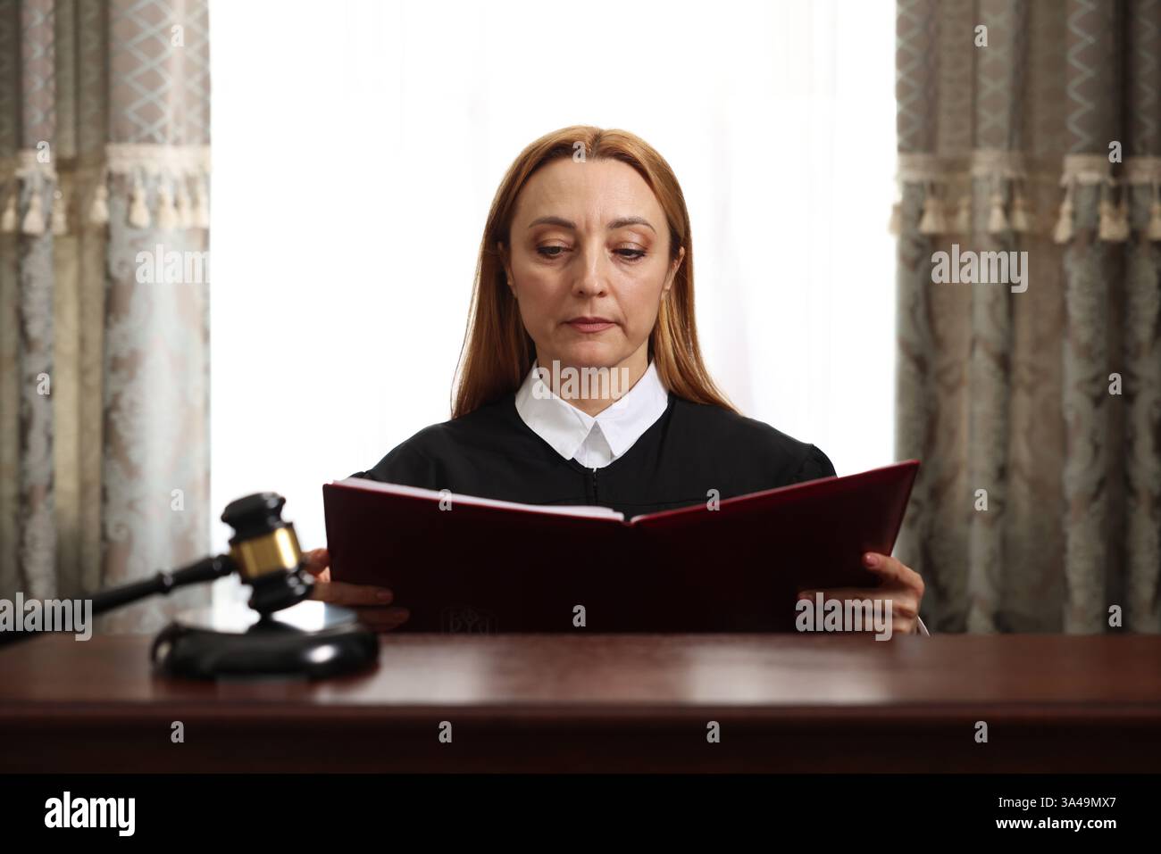 Judge with folder of documents at wooden table in courtroom Stock Photo ...