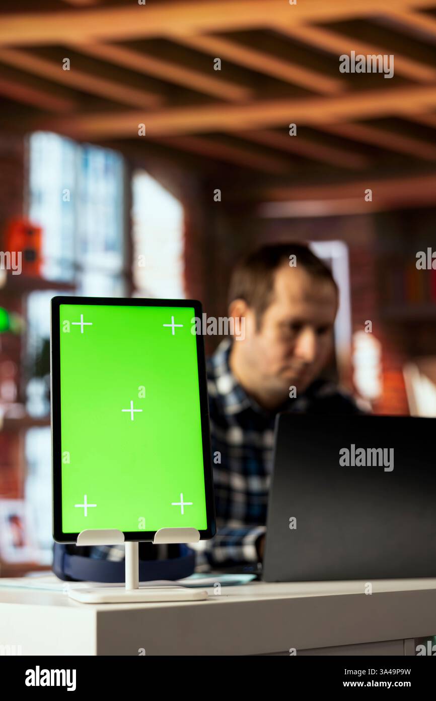 Focus on green screen tablet used by man in blurry background using ...