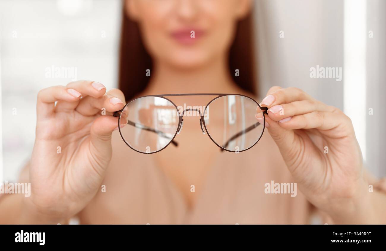 Woman holding eyeglasses in a bright indoor setting during daytime ...