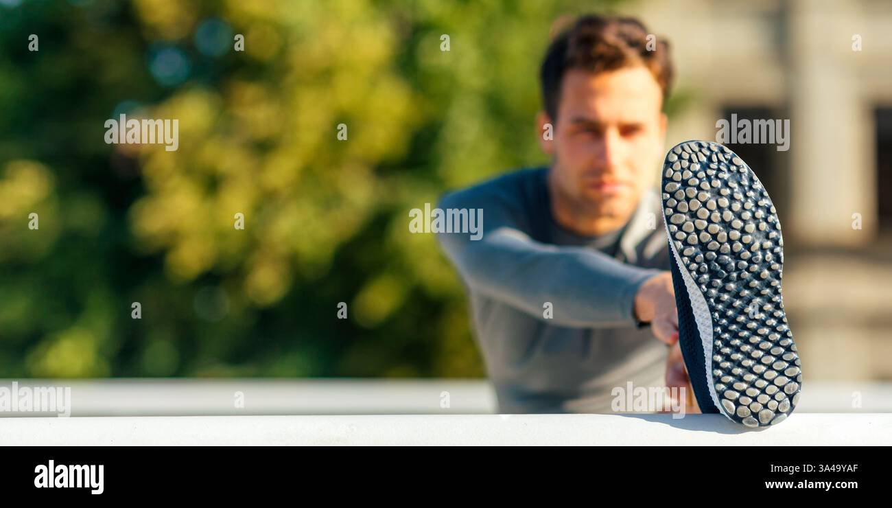 Muscular young man in sportswear lifts his leg on railing Stock Photo ...