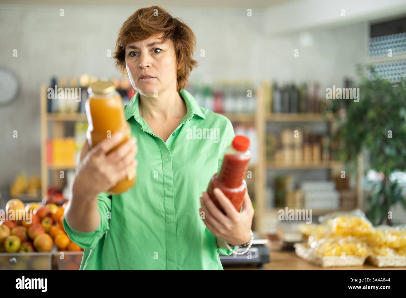 Grocery shopping at supermarket - woman chooses juice, tomato ...